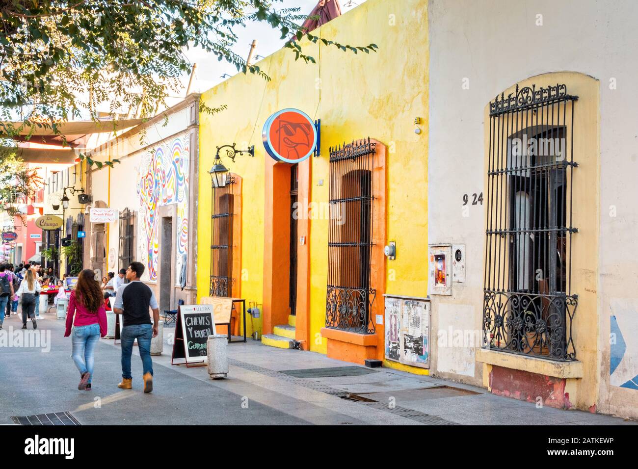 People walk past brightly painted Spanish colonial style buildings in ...