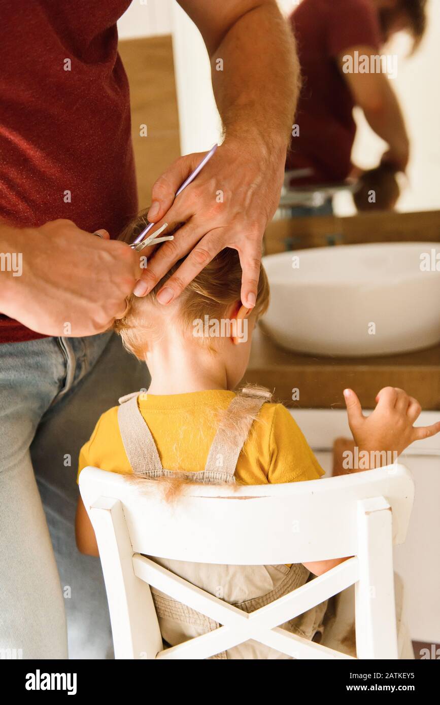 Dad cutting hair to little son Stock Photo - Alamy