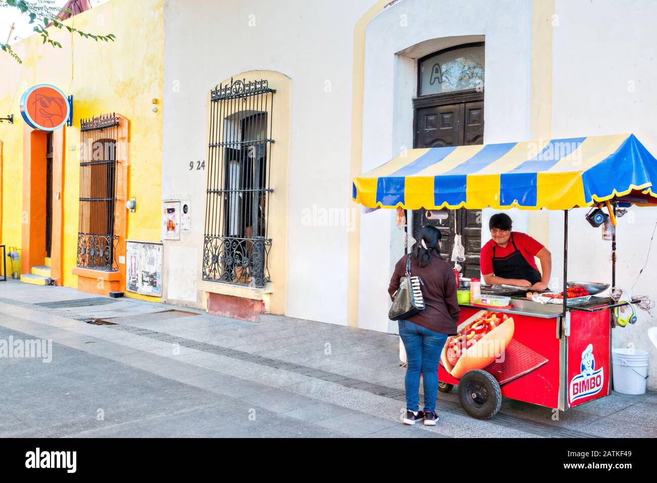 A food vendor selling hot dogs in front of a Spanish colonial style ...