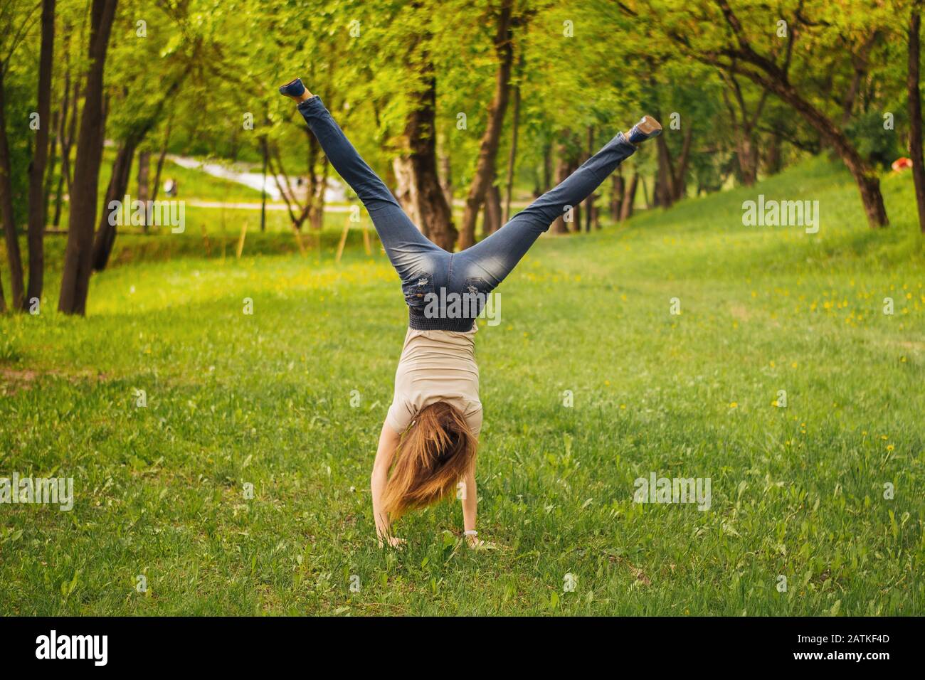 Girl makes an acrobatic wheel. On the grass Stock Photo - Alamy