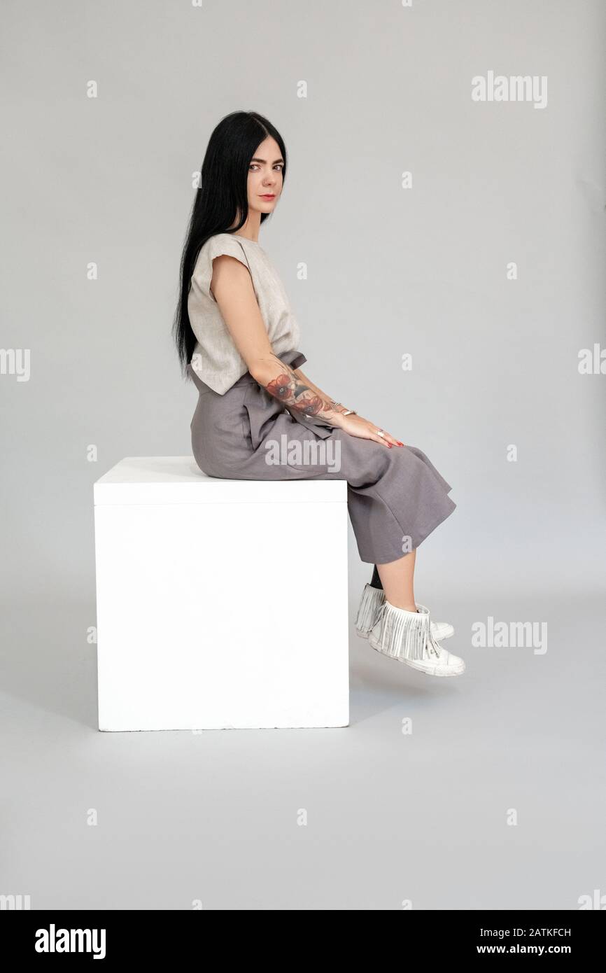 Freestyle. Diverse girl with leg prosthesis sitting on white cube ...