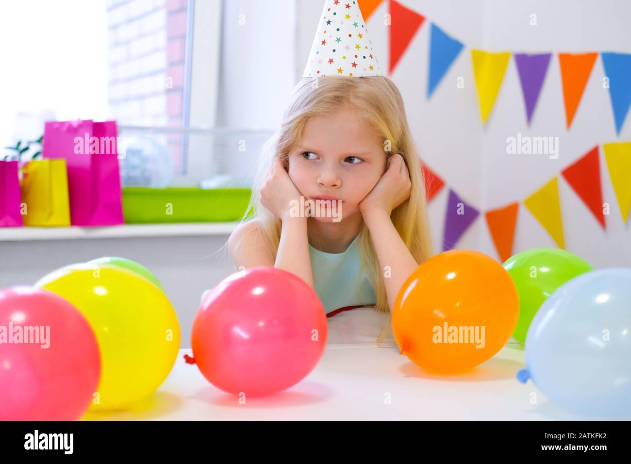 Unhappy blonde caucasian girl with boring face near birthday rainbow ...