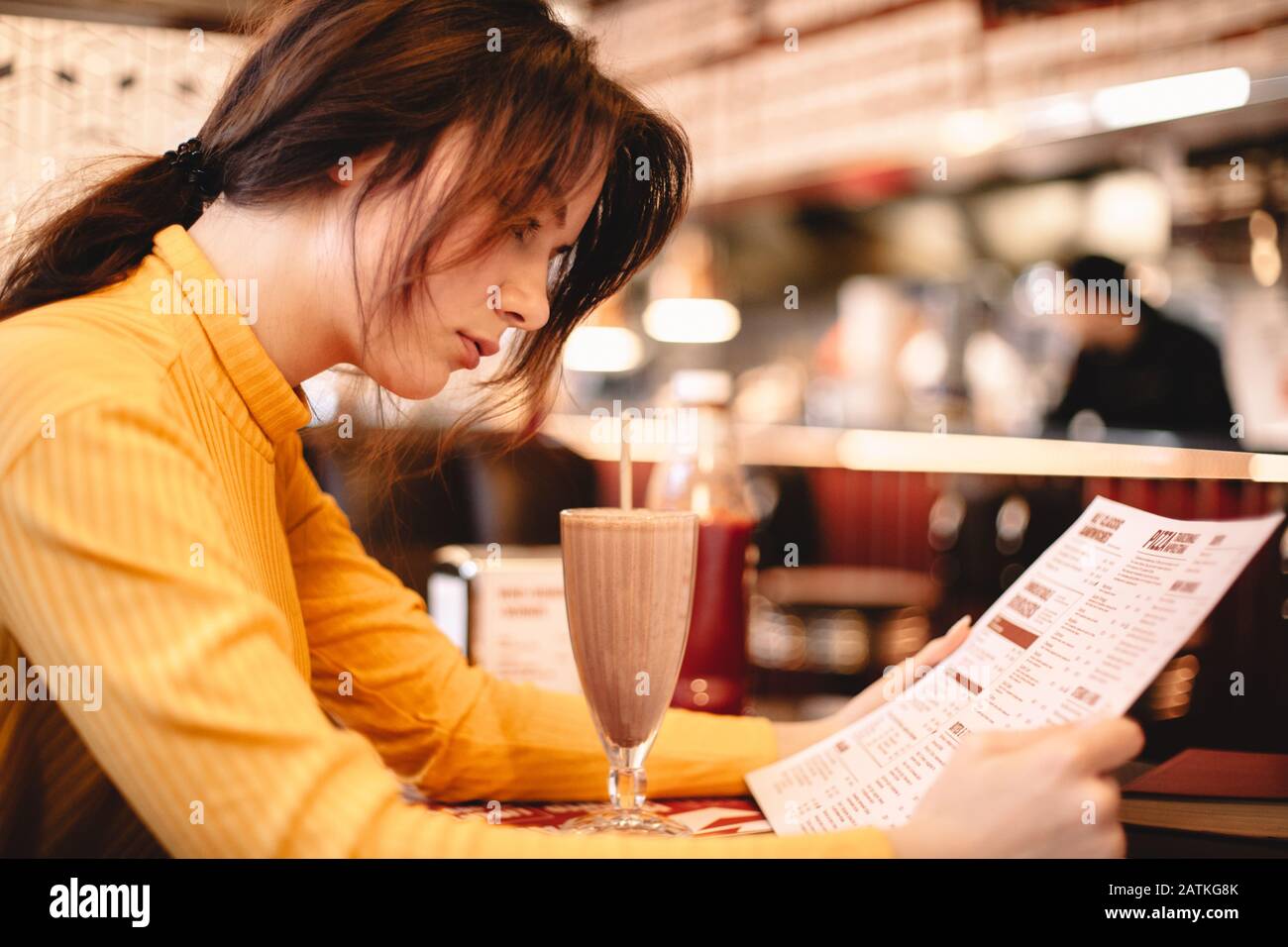 Teenage girl reading menu while sitting in restaurant Stock Photo - Alamy