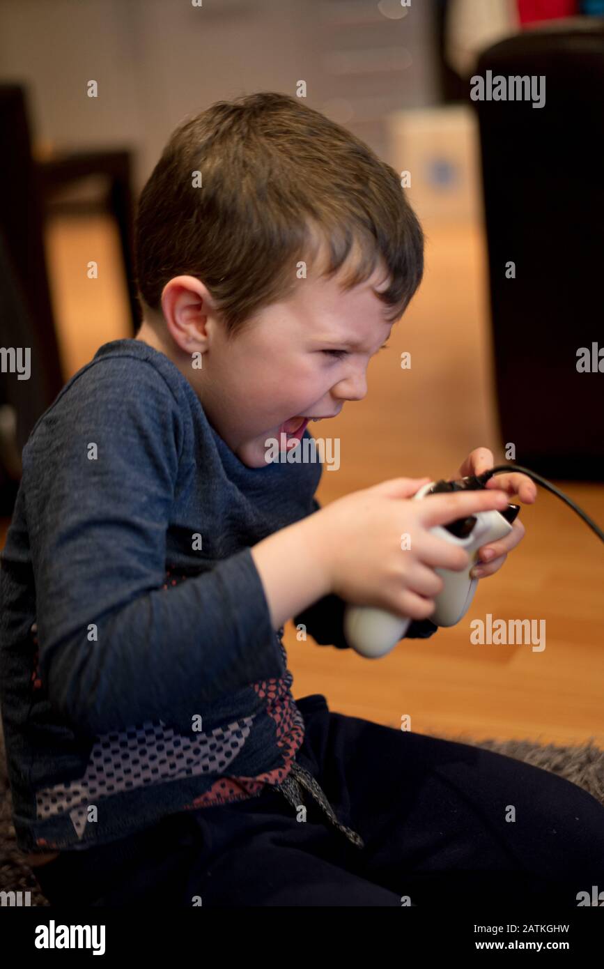 Small boy playing electronic entertainment games console with a white ...