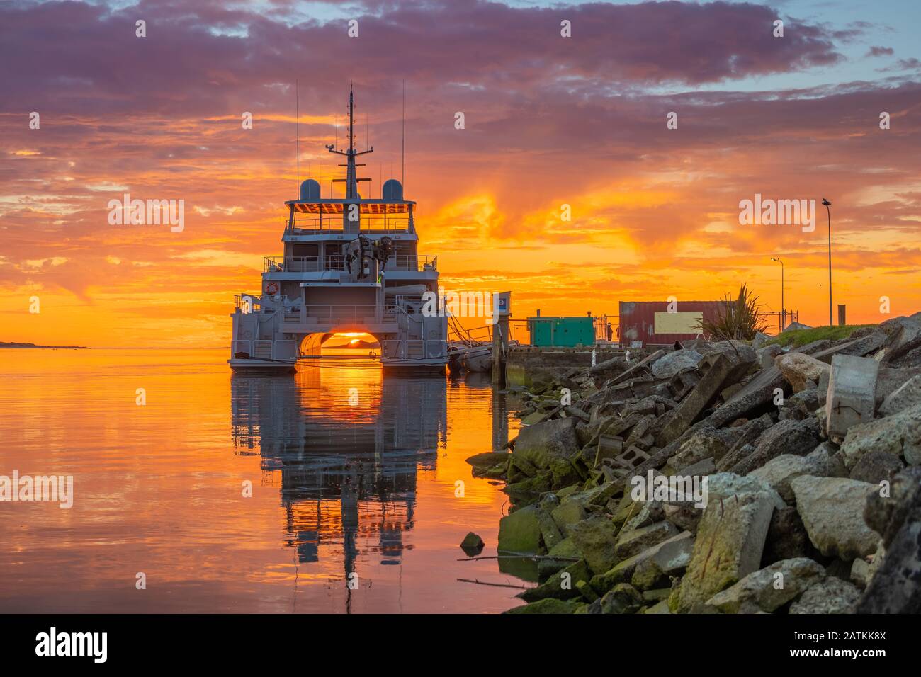 Twin hull boat tied up at Foxton Beach wharf, with a nice sunset Stock ...