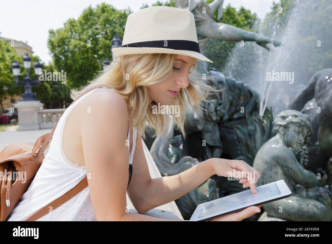 female tourist using tablet while resting next to a fountain Stock ...