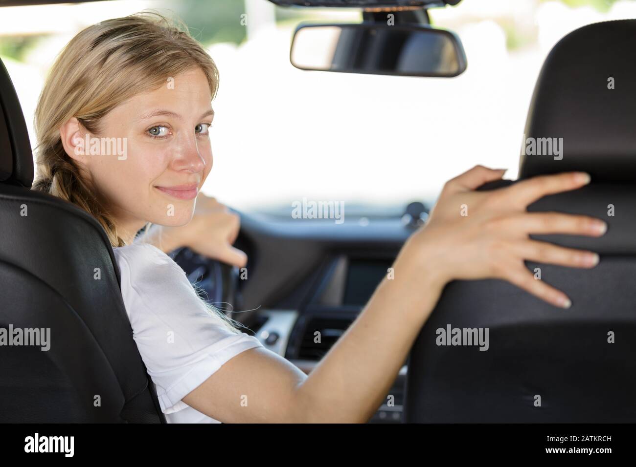 beautiful woman looking back while driving car Stock Photo - Alamy
