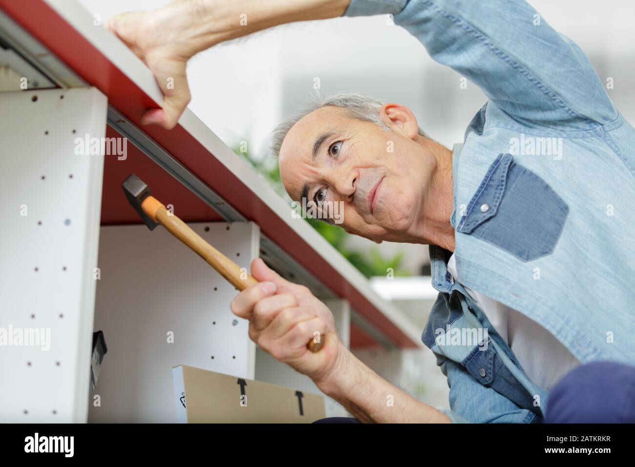 senior man using hammer to fit kitchen cupboard Stock Photo - Alamy