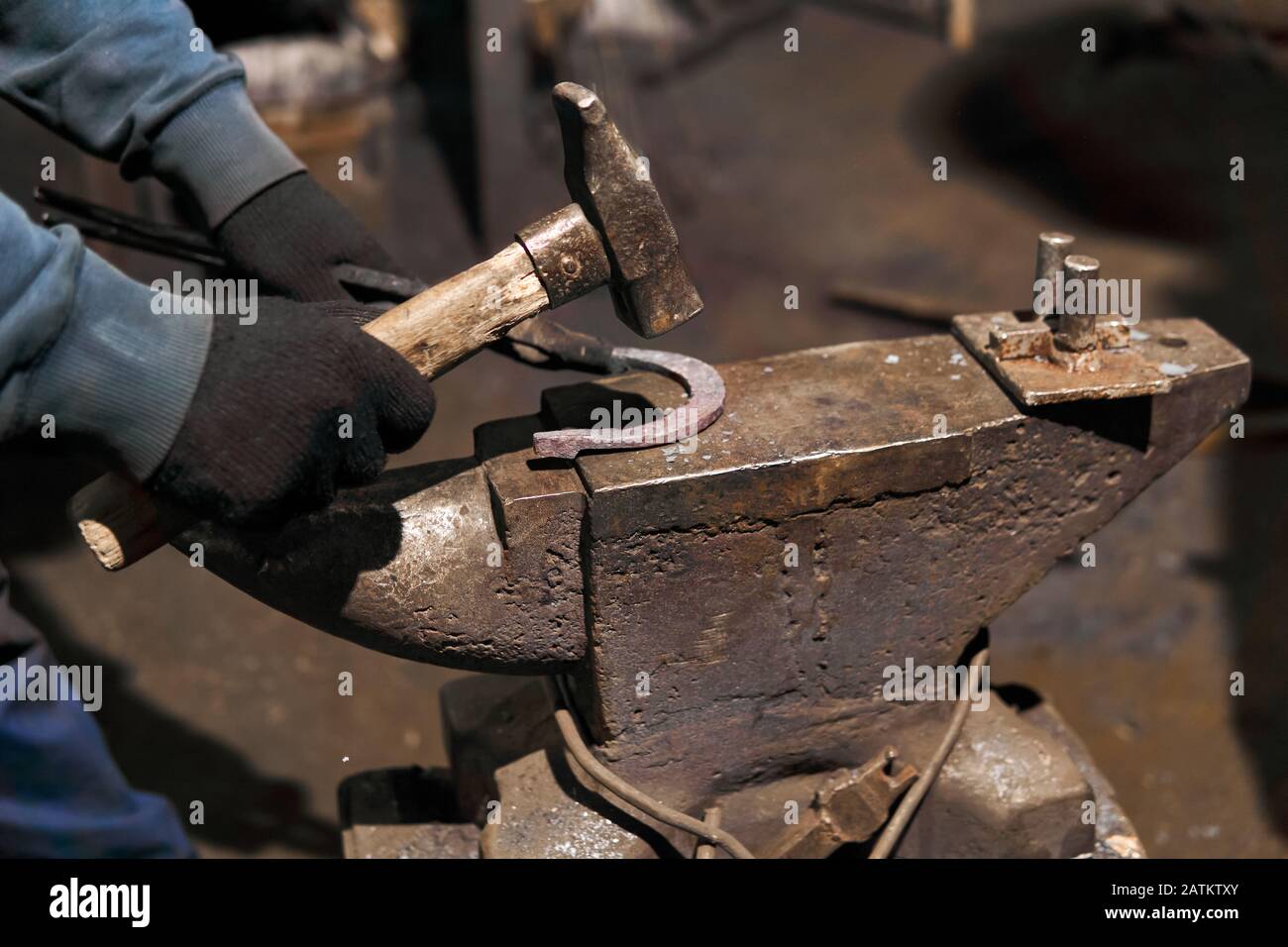 blacksmith forges a horseshoe on the anvil with bending drift, close-up ...