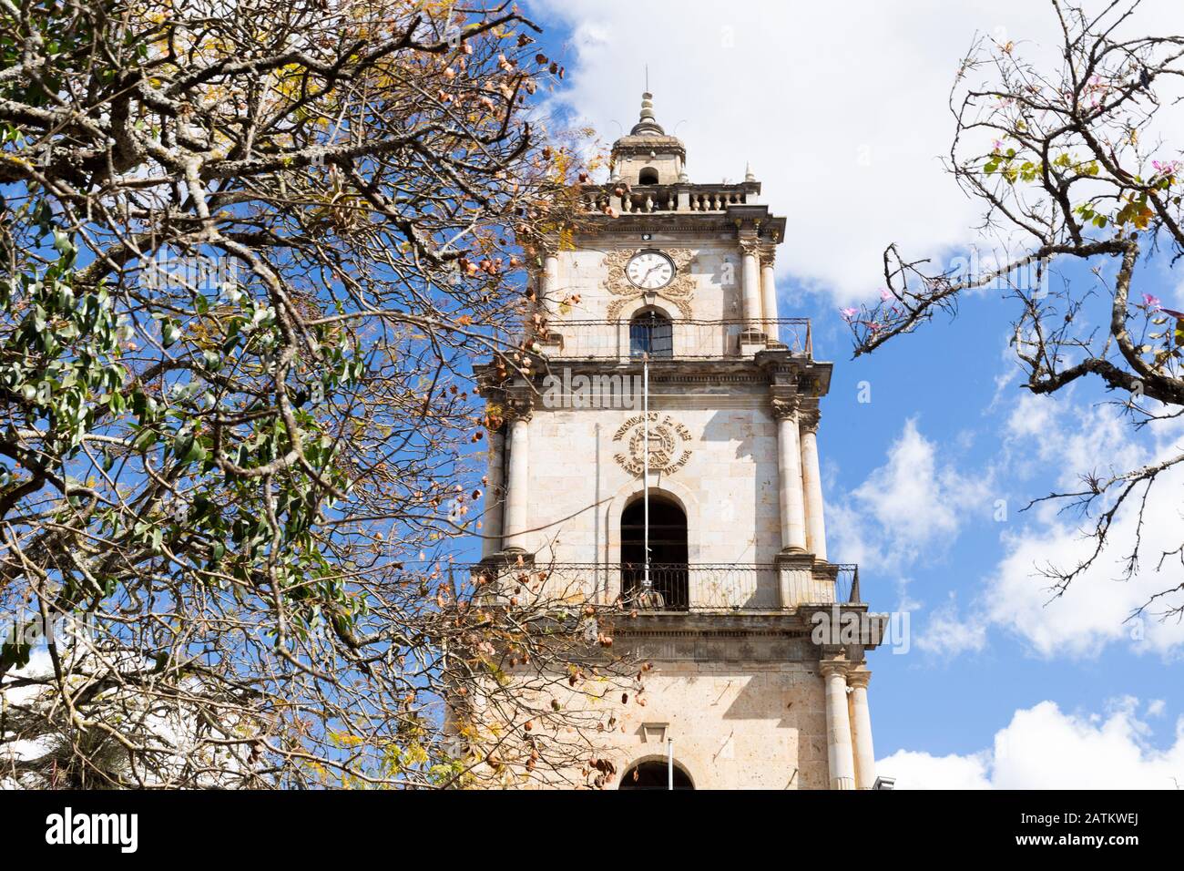 old stone tower with clock surrounded by trees in autumn in Guatemala ...