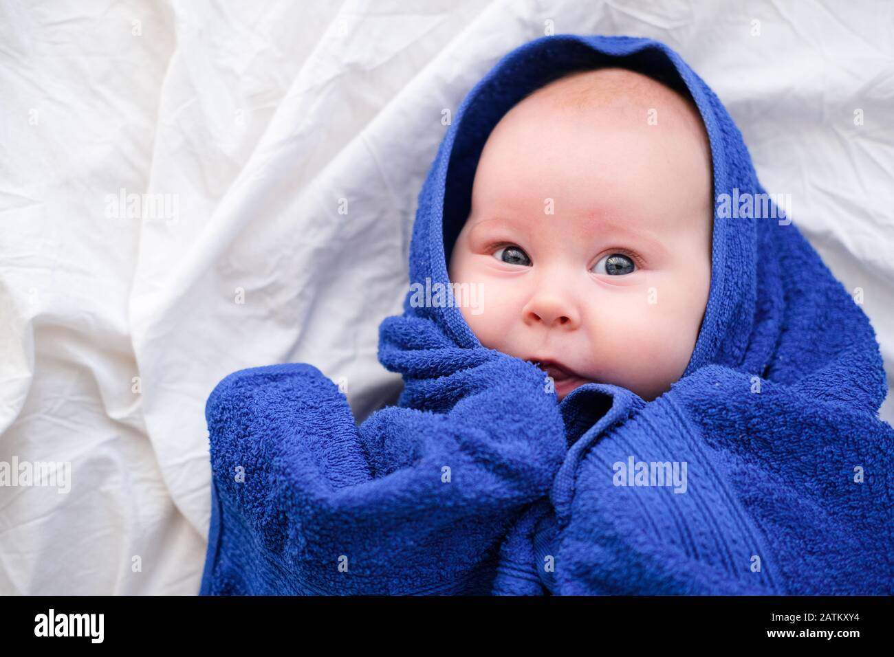 Bath time. Cute smiling caucasian infant baby looking at camera wrapped ...