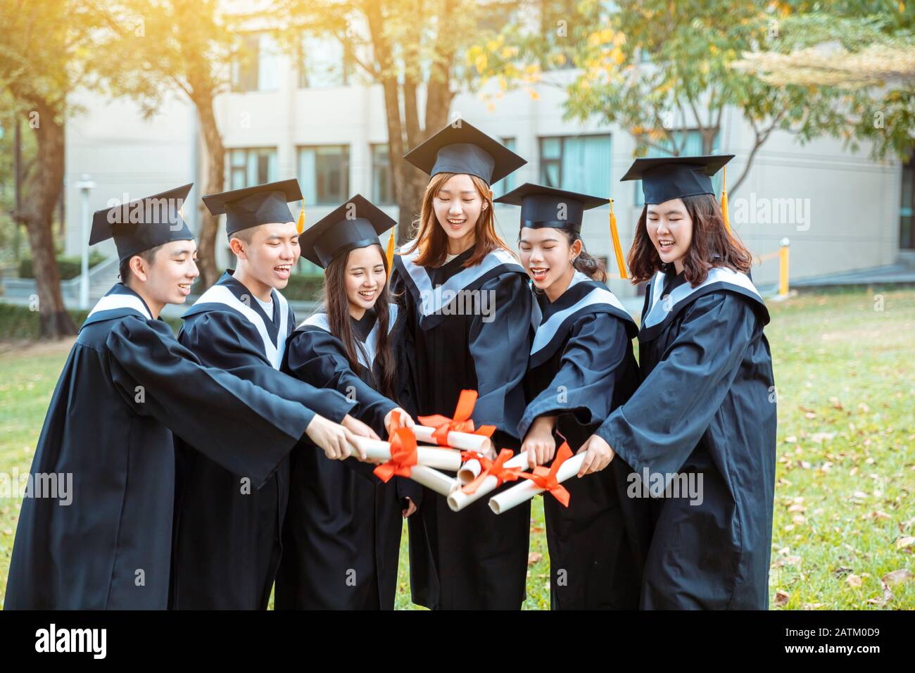 happy students in graduation gowns holding diplomas on university ...