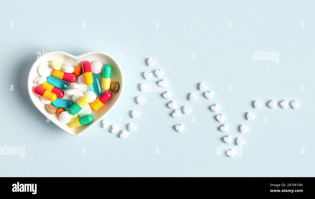 Heartbeat line made of heart shaped pills and bowl with colorful ...