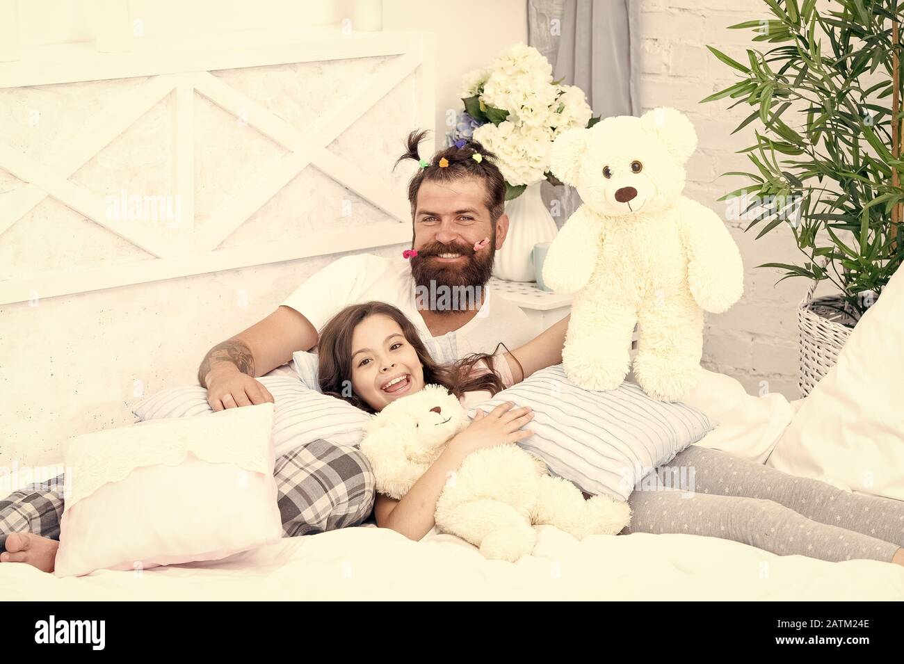 Dad and girl relaxing in bedroom. Pajamas style. Father bearded man with funny hairstyle ...