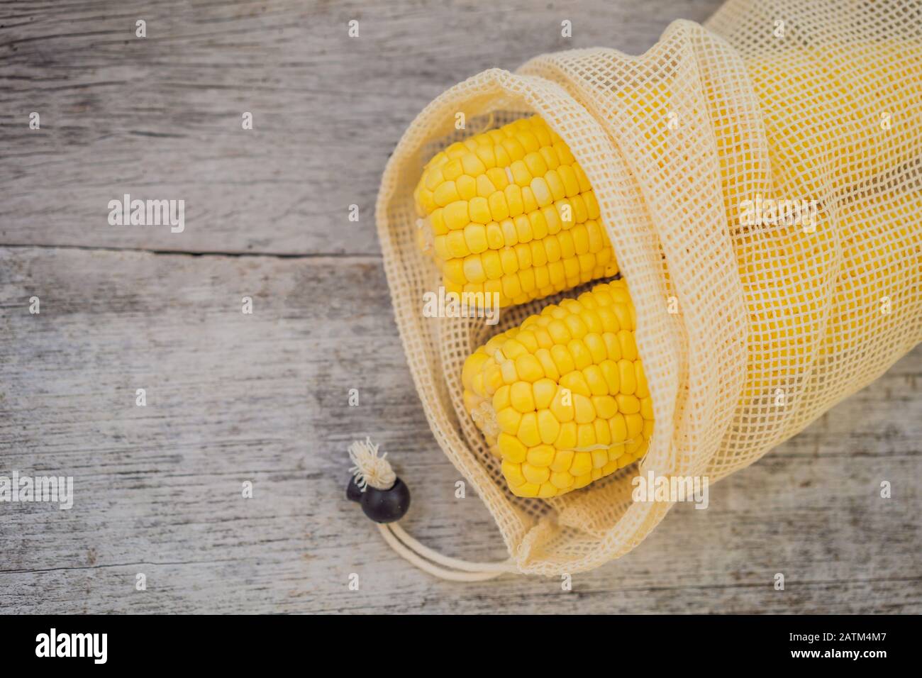 Corn in a reusable bag on a stylish wooden kitchen surface. Zero waste ...