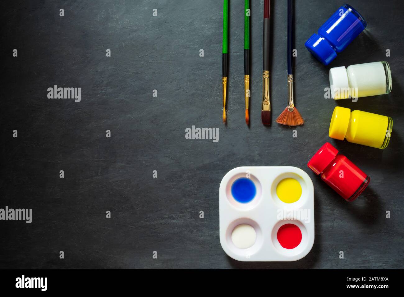 Palette and poster color bottle with paint brush on black cement ...