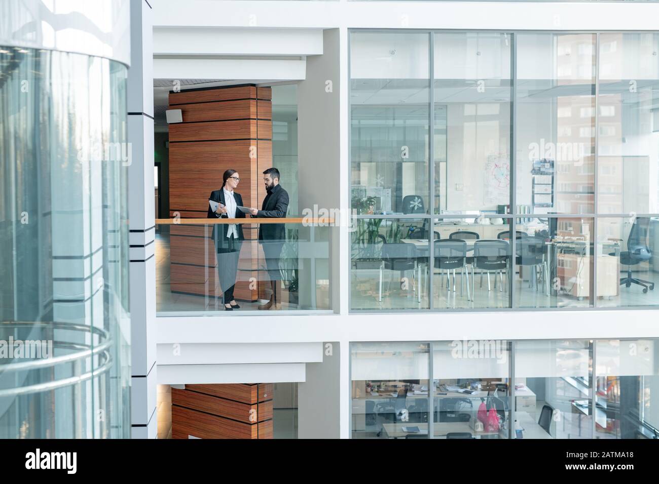 Young office workers standing on balcony of business center and sharing ...