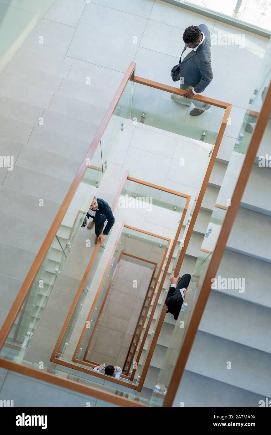 Conceptual image of modern business people moving over office stairwell ...