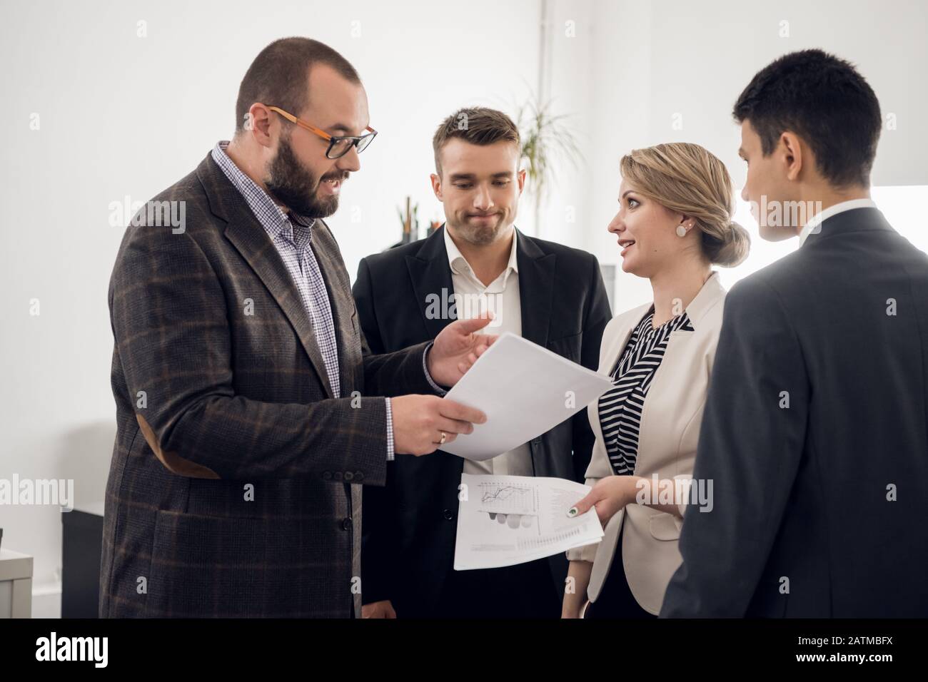 Office workers in suits stand together and discuss documents in the ...