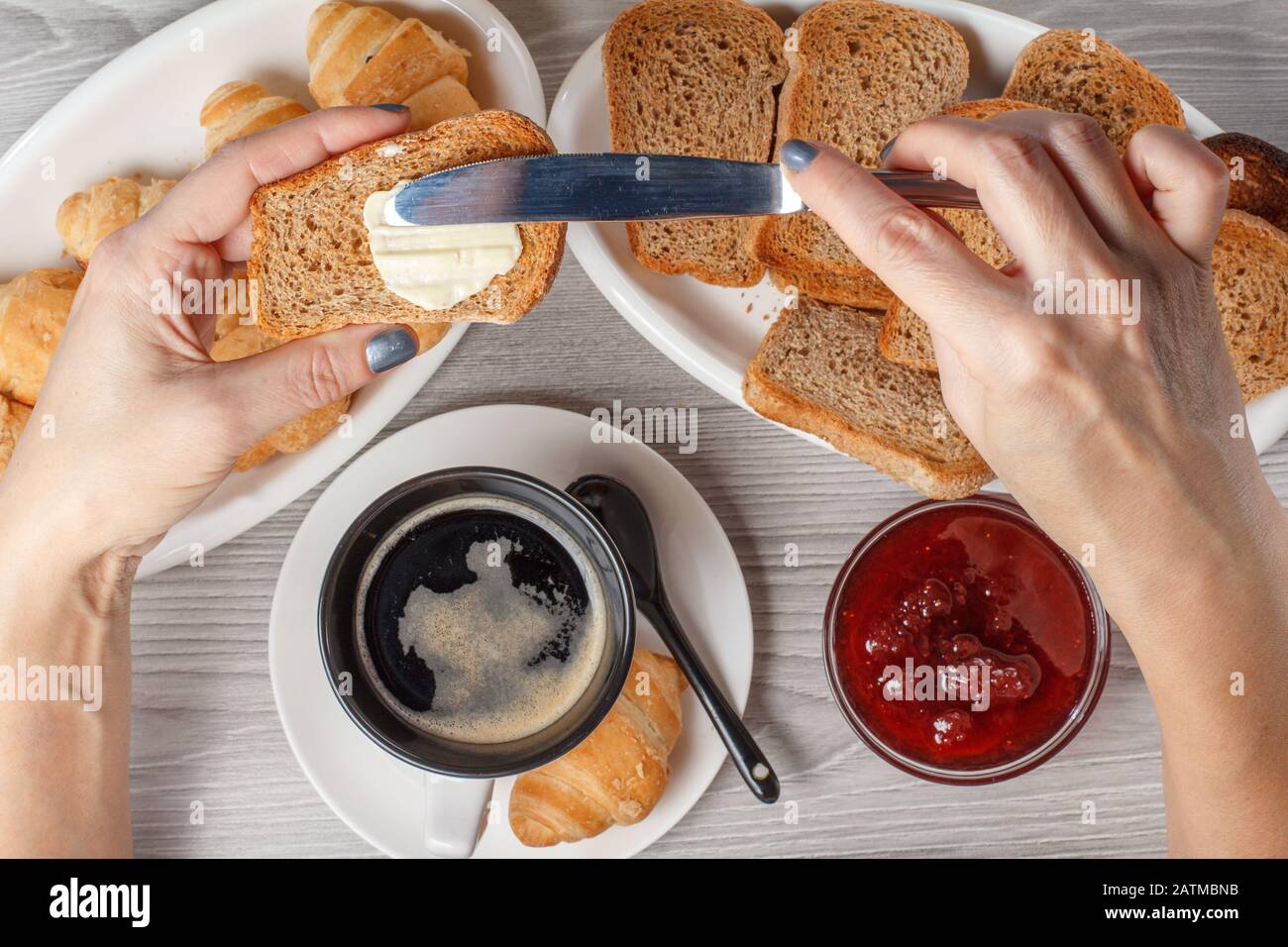 Male hands spreading butter on toast with cup of black coffee and ...