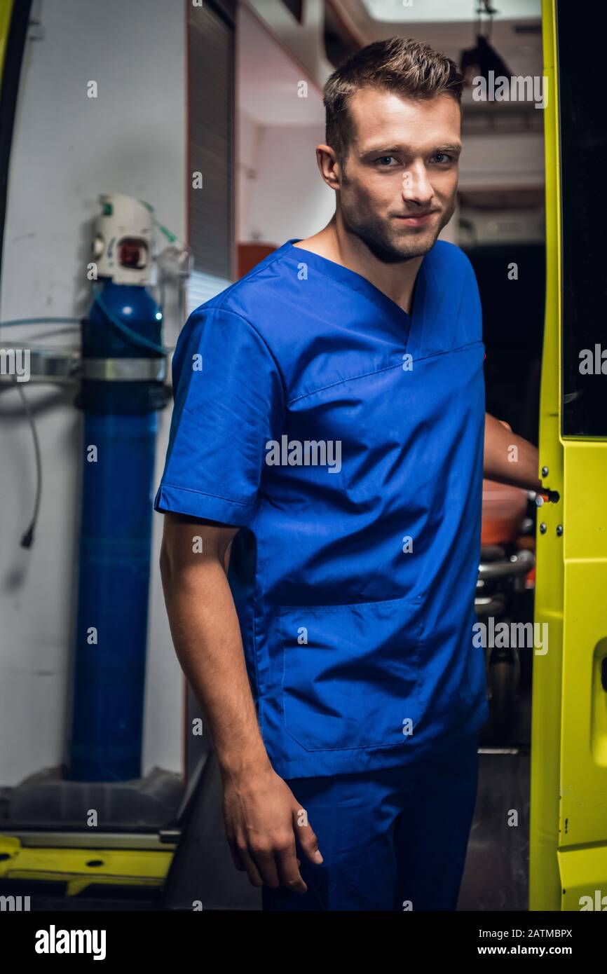 Corpsman in medical uniform stands and looks at camera in the ambulance ...