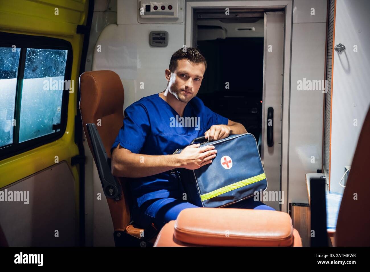 Corpsman in medical uniform sits in the ambulance car and holds medical ...