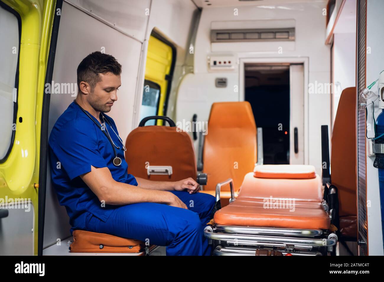 Tired corpsman in uniform sits inside the ambulance car and think Stock ...