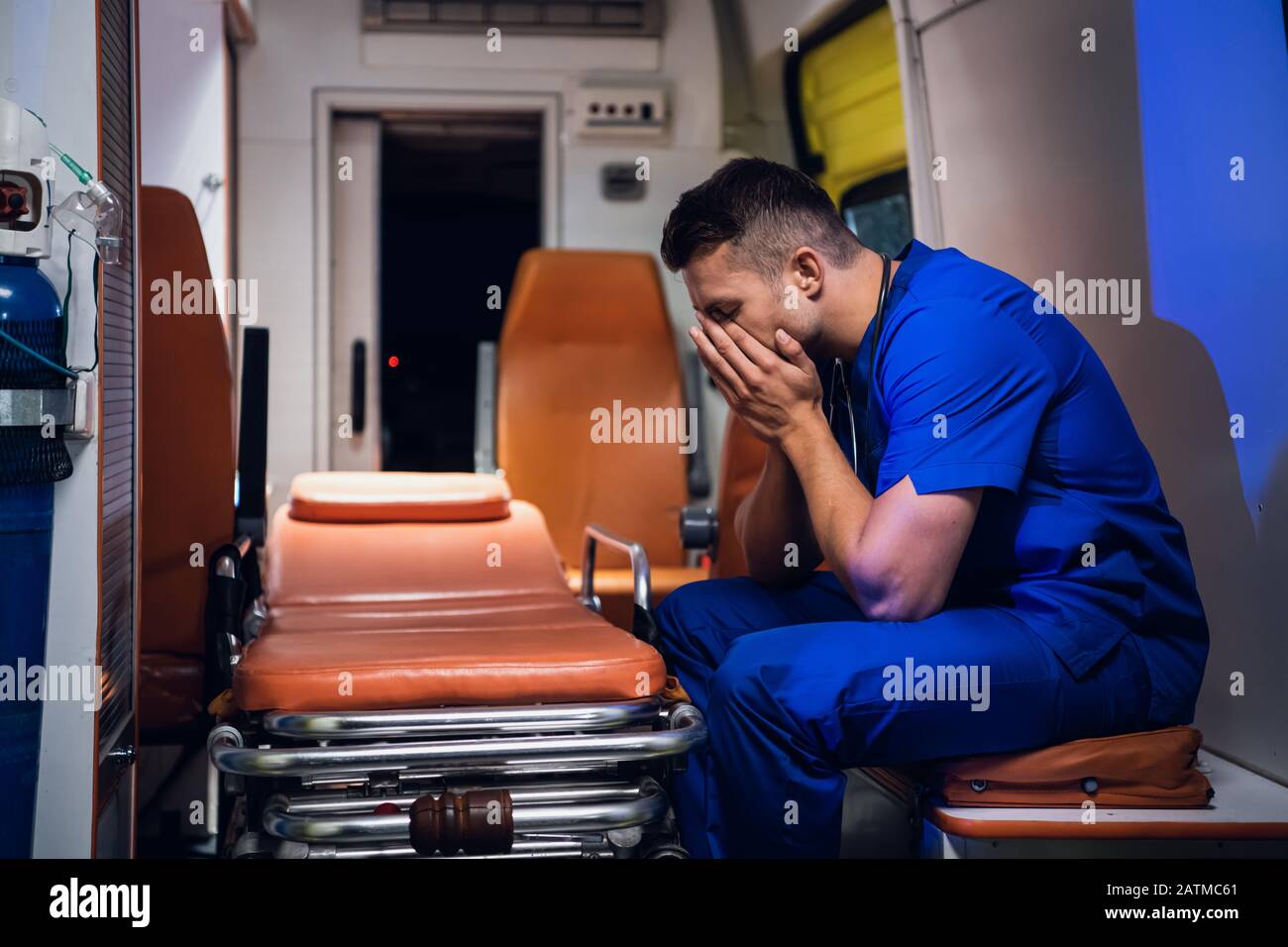 Tired corpsman in medical uniform sits inside the ambulance car at ...