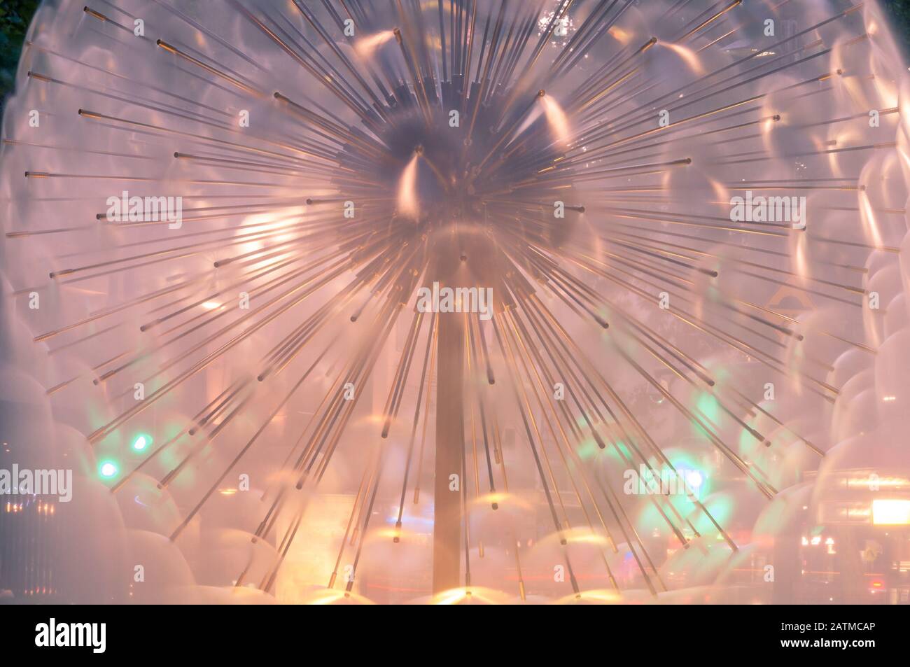 Close up of round dandelion like fountain. Illuminated water stream ...