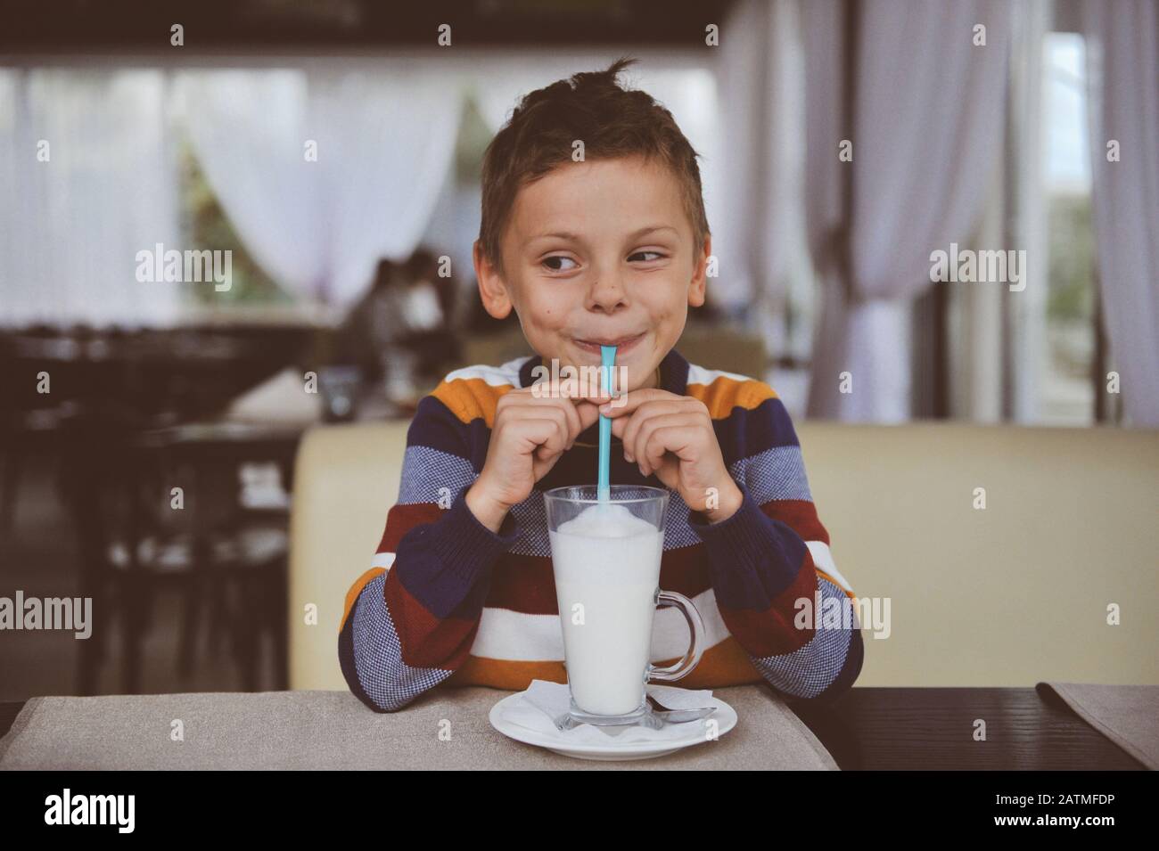 happy smiling little boy in colorful sweater drinking milk shake ...
