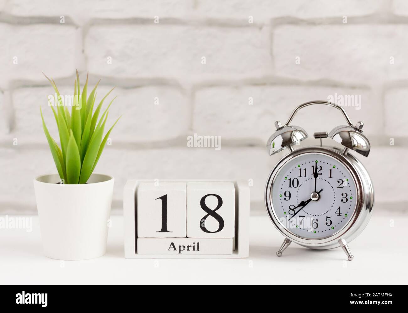 April 18 on a wooden calendar on a white background.Alarm clock and ...