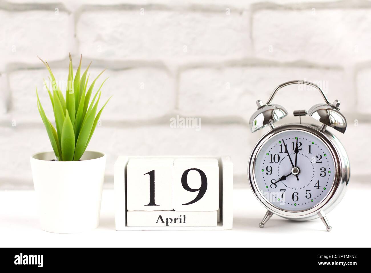 April 19 on a wooden calendar on a white background.Alarm clock and ...