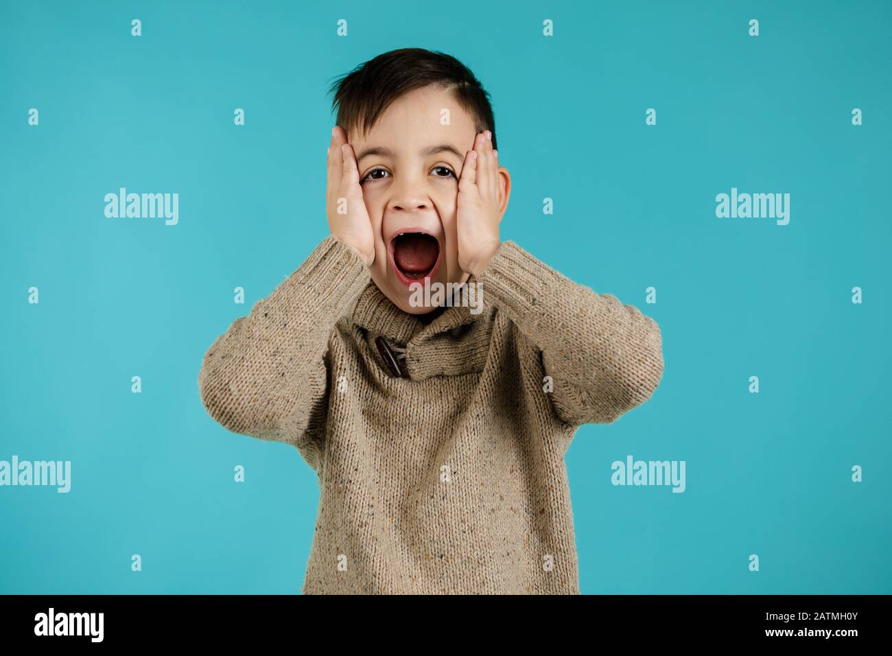 happy surprised little child boy looking to camera on blue background ...