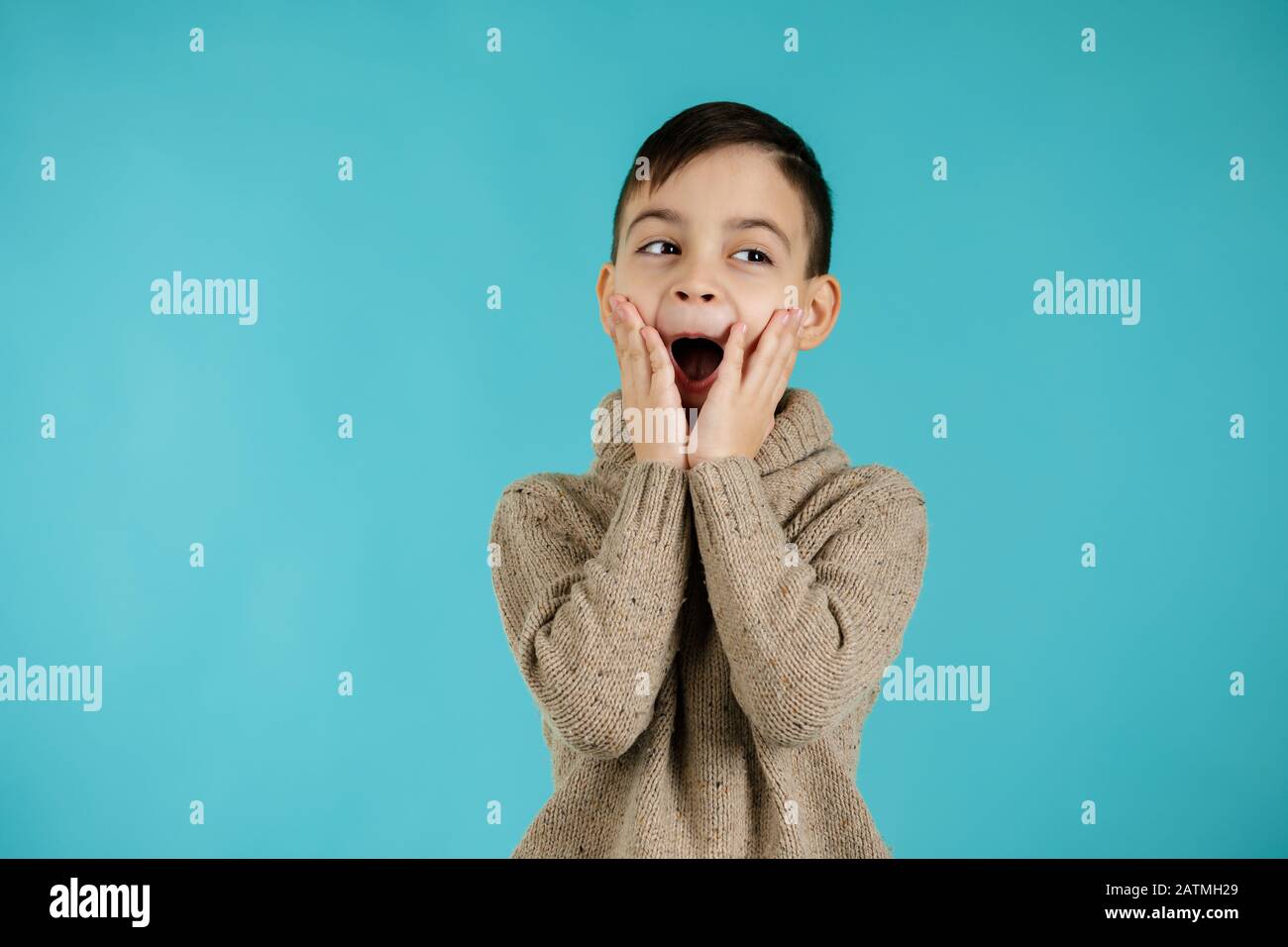 happy surprised little child boy looking to camera on blue background ...