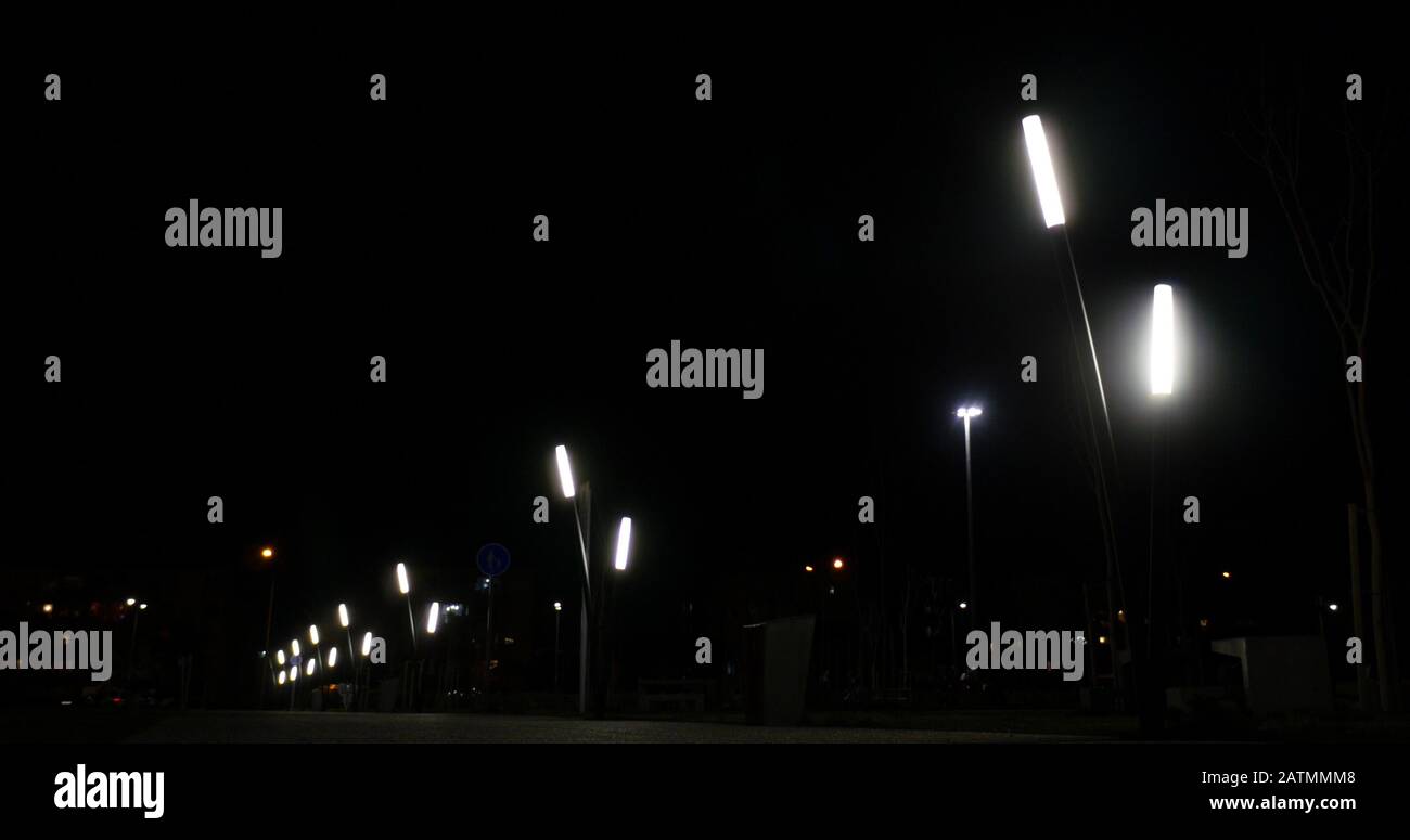 Public lights in the dark night street and cars passing trough on the ...