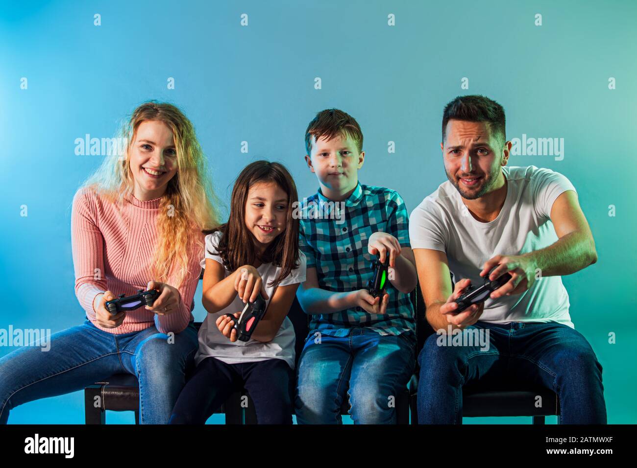 Young cheerful parents and kids playing video game together Stock Photo ...