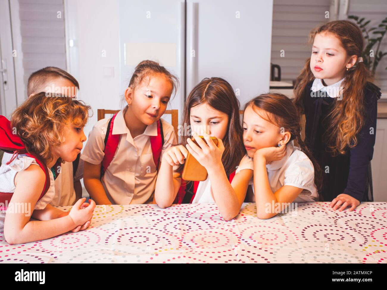 Cute pupils talking and using smartphone during break. Happy friends ...
