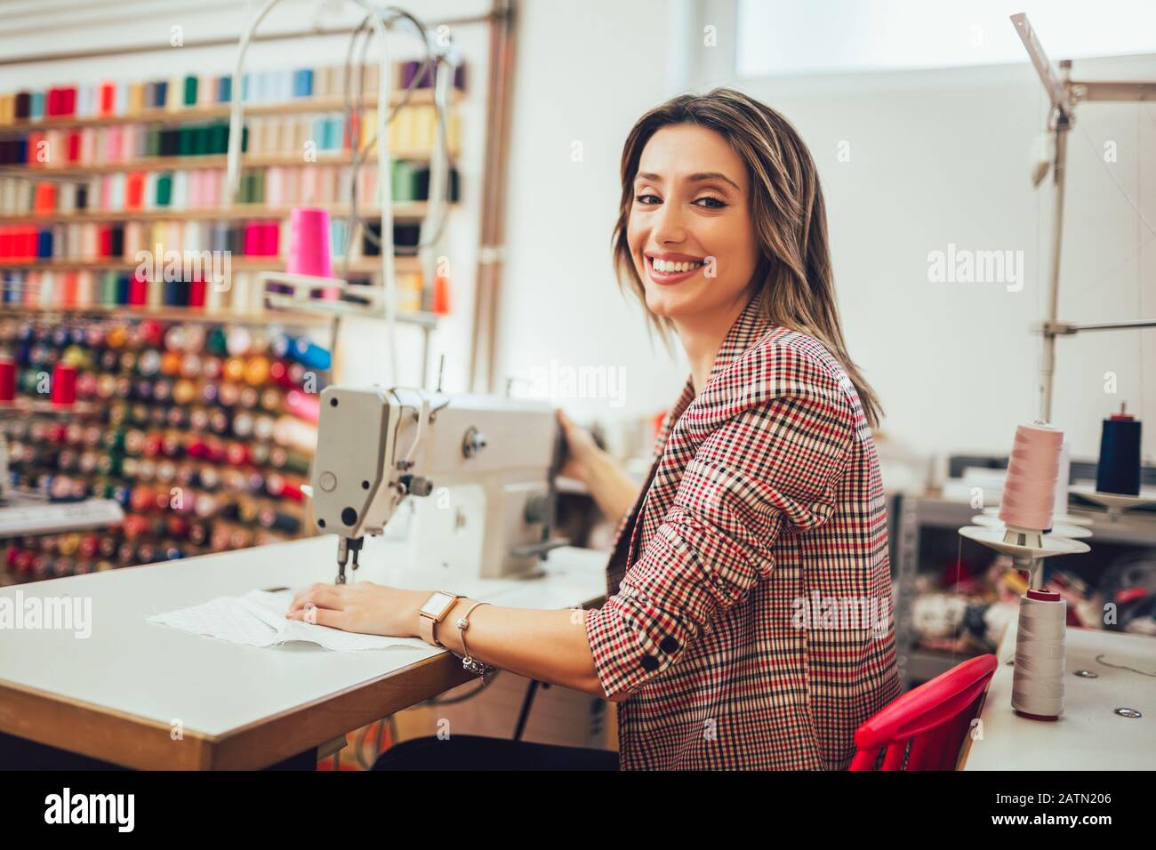 Portrait of happy dressmaker woman in studio. Background of colorful ...