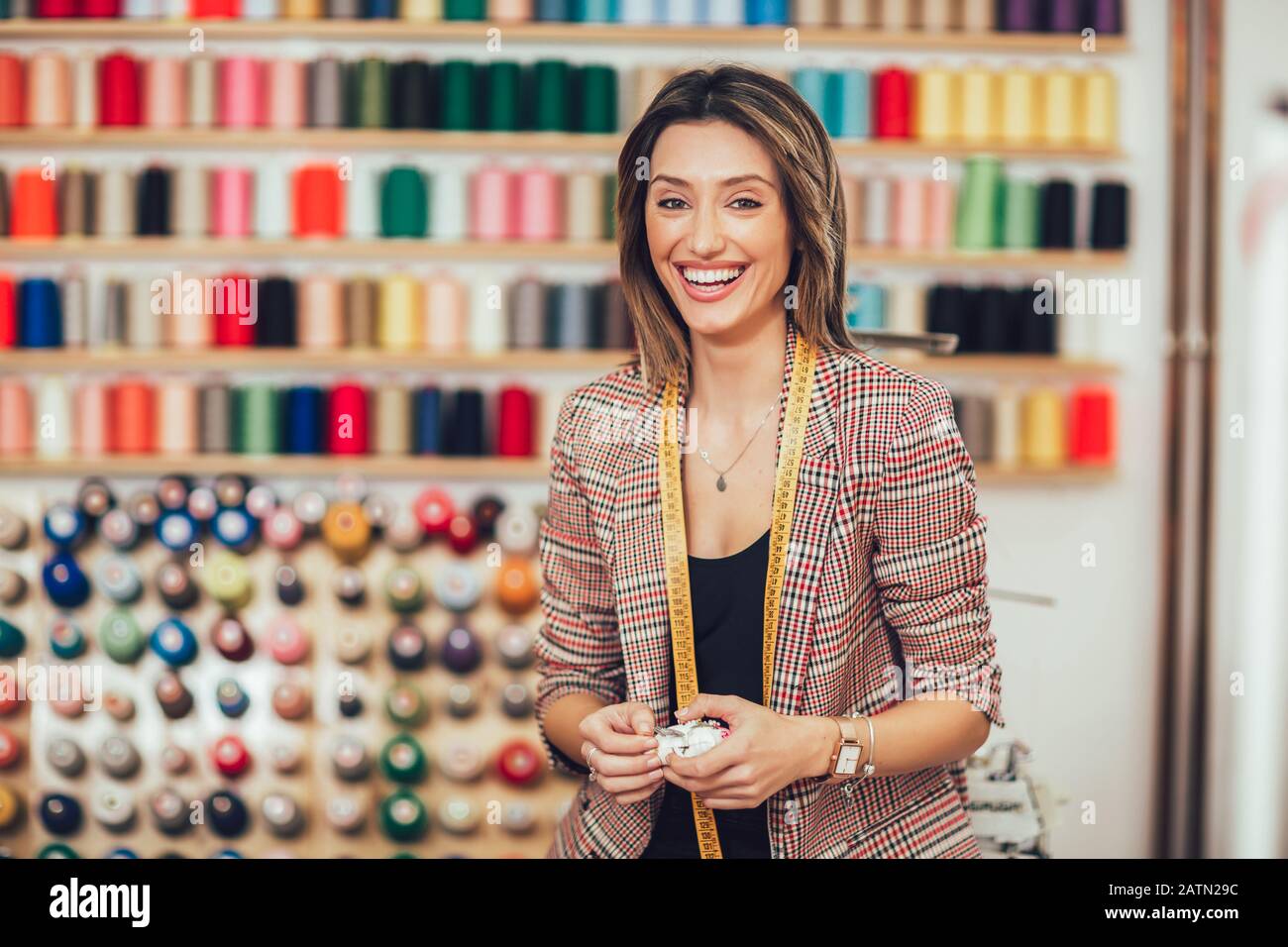 Portrait of happy dressmaker woman in studio. Background of colorful ...