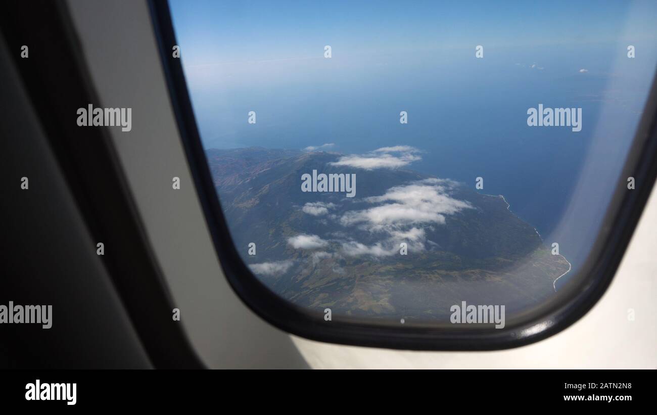 aircraft porthole window with blue sea or ocean in it and small ...