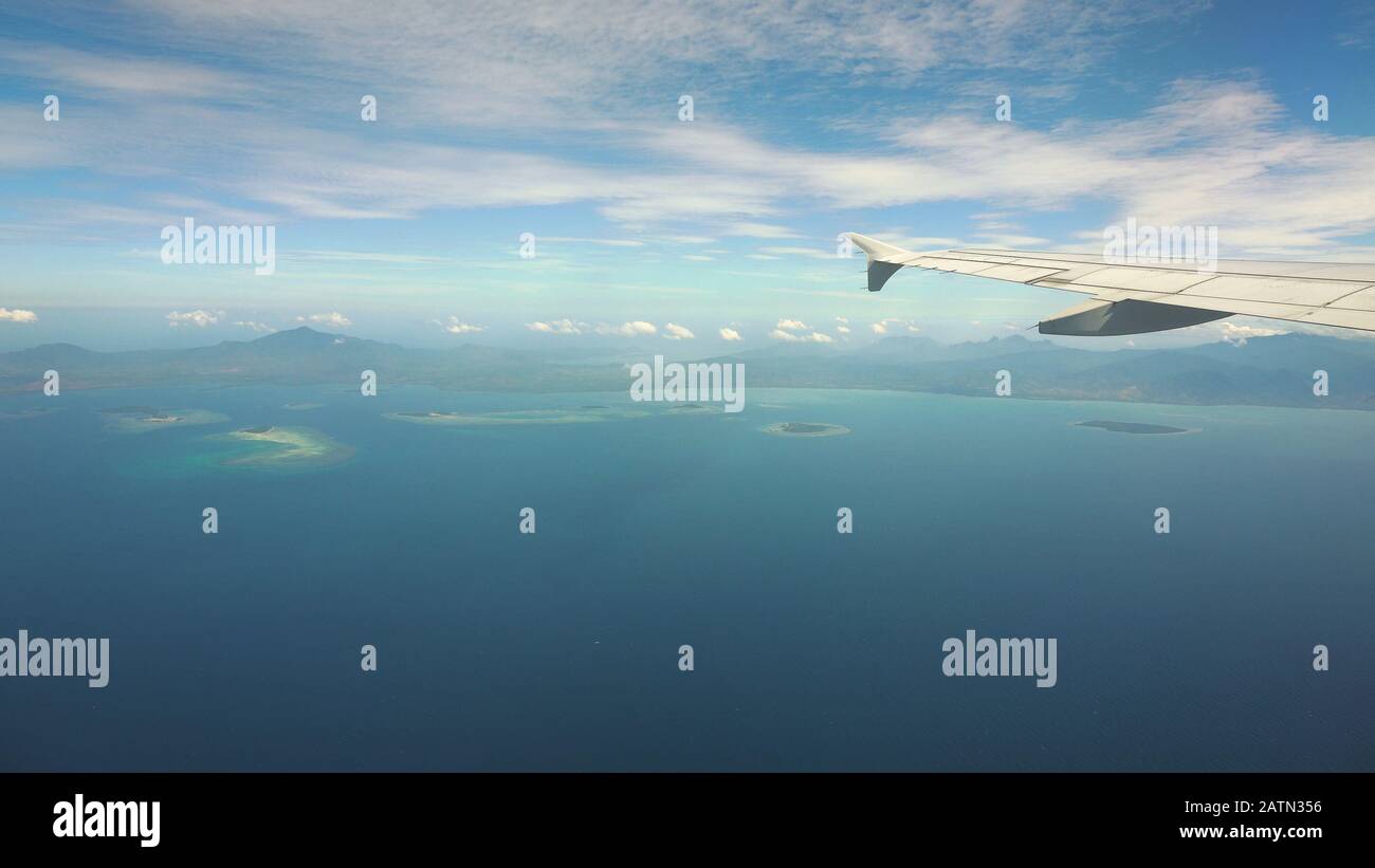 Airplane flying over blue sea and island. Looking through window ...