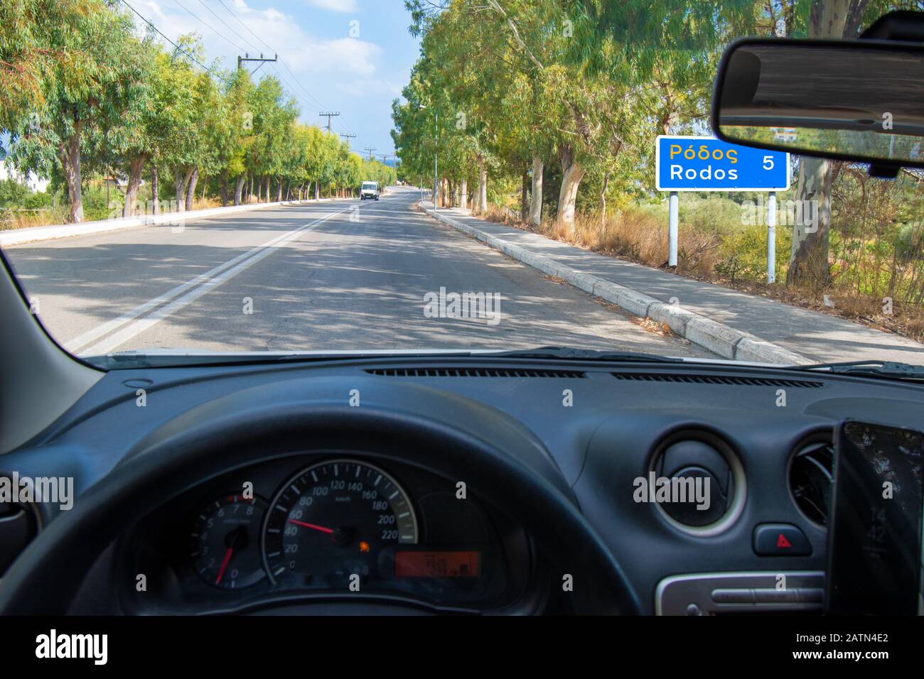View from inside of car, blue traffic sign with directions to Rhodes ...