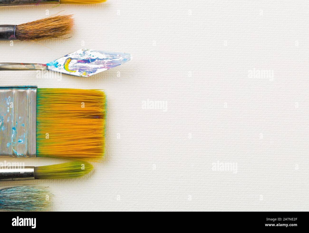 Artistic art supply utensils with paintbrushes on white canvas ...