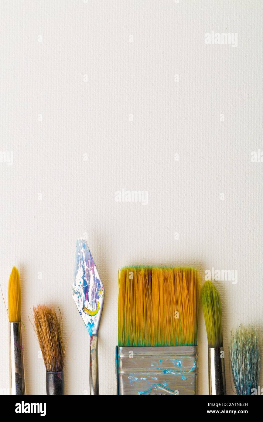 Artistic art supply utensils with paintbrushes on white canvas ...