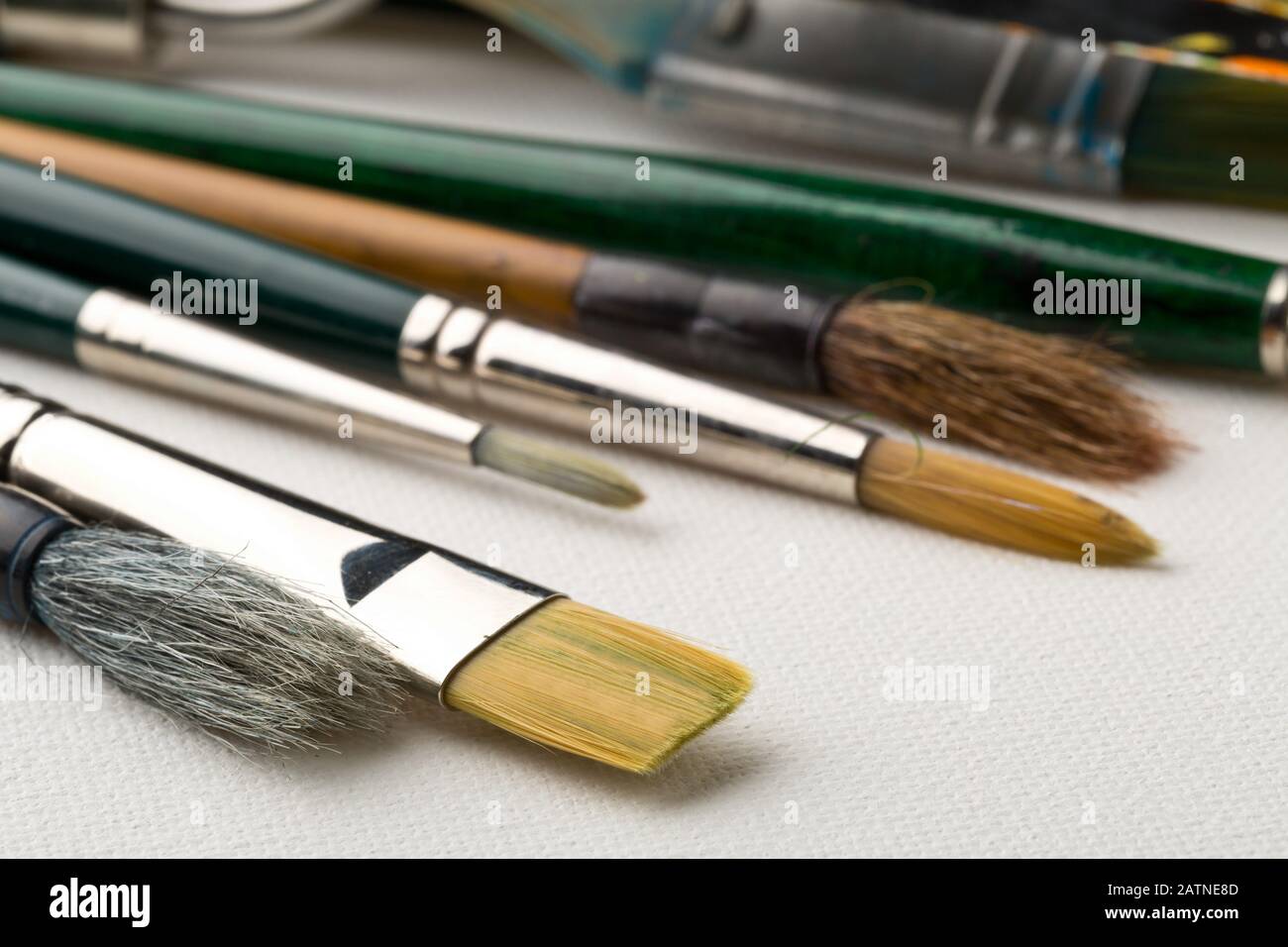 Artistic art supply utensils with paintbrushes on white canvas ...