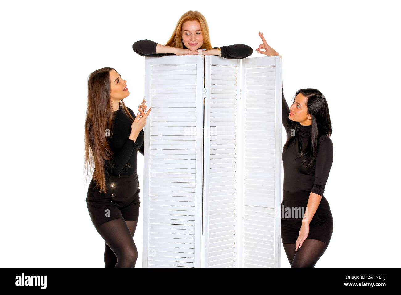 three young female friends pose together in the Studio. three friends pose and joke. isolated ...