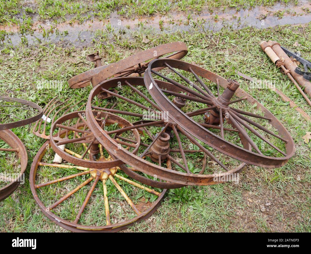 Old rusty wagon wheels piled on a wet muddy ground Stock Photo - Alamy