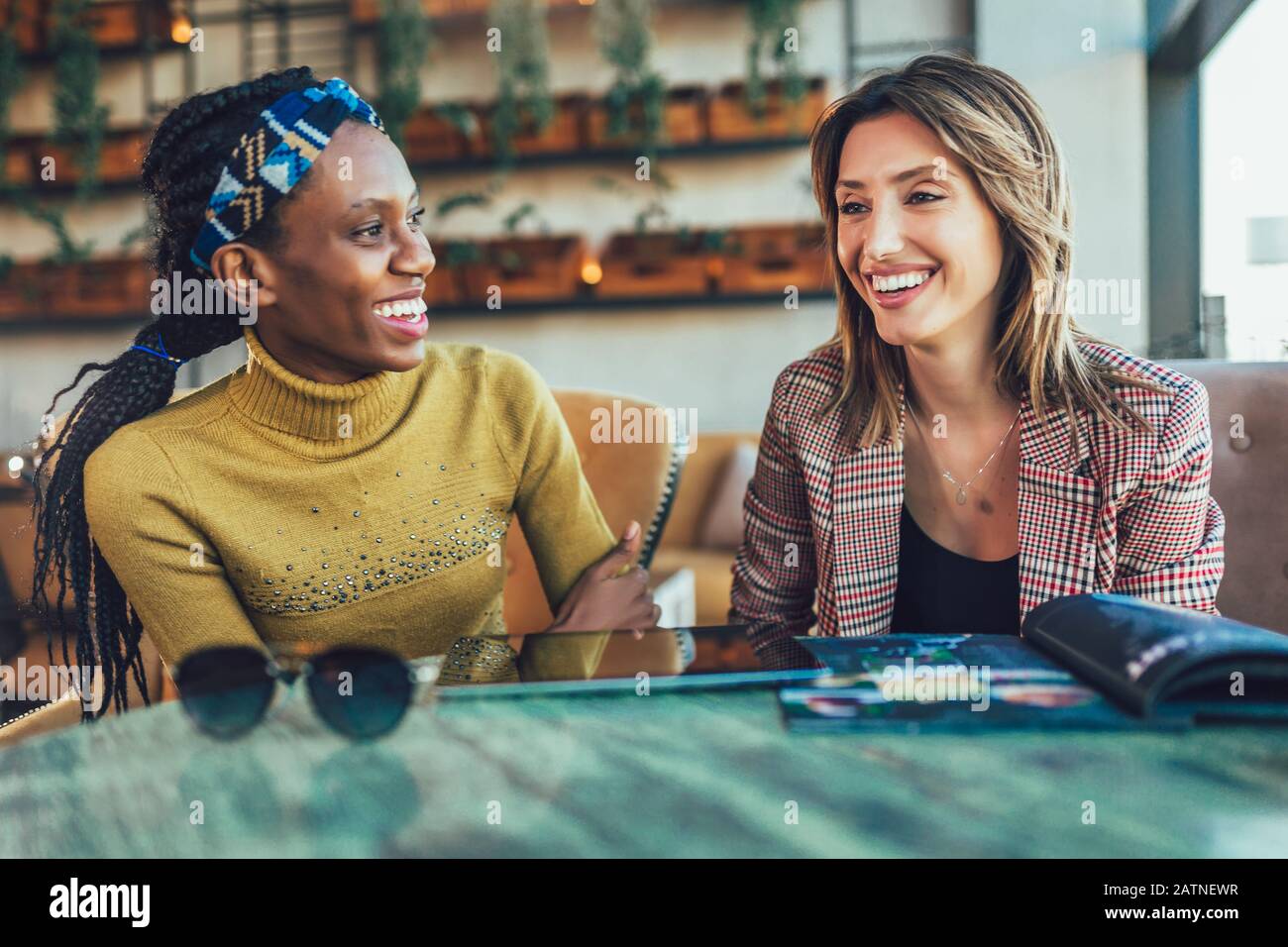 Two female friends talking at a coffee shop Stock Photo - Alamy