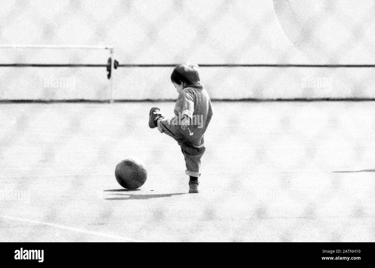 A young boy kicks a ball in a play ground Stock Photo - Alamy