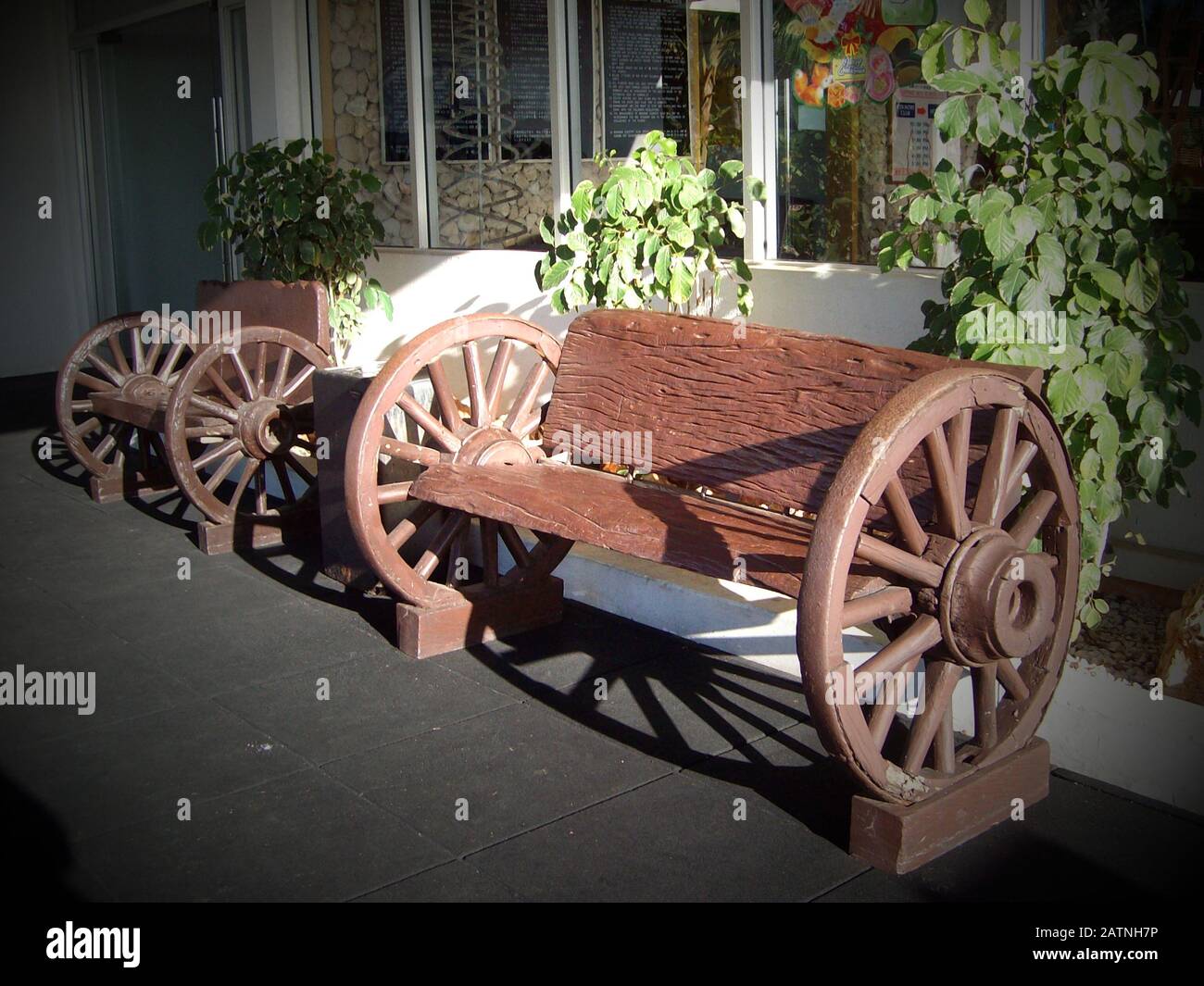 Wooden benches with wagon wheels outside a structure Stock Photo - Alamy